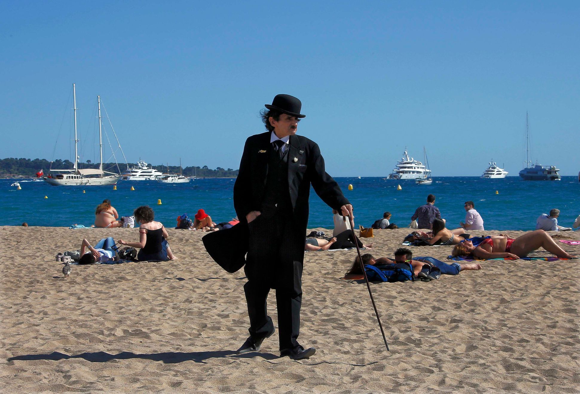 A man dressed as Charlie Chaplin walks on the beach during the 67th ...